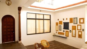 Um quarto com uma grande janela, uma porta de madeira e uma parede com diversos objetos emoldurados.