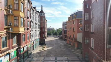 Vista da rua com edifícios altos, céu claro e um prédio distante.