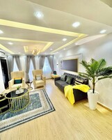 Uma sala de estar moderna com um sofá, poltronas, uma mesa de centro e uma TV.