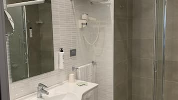 Uma casa de banho moderna com um espelho grande, uma pia, uma cabine de duche e um porta-toalhas.