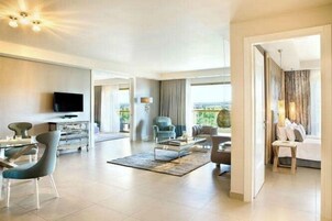 Uma sala de estar ampla com televisão de tela plana, móveis modernos e grandes janelas com vista para o exterior.