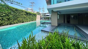 Um edifício moderno com piscina, cercado por vegetação e céu claro.