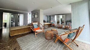 Uma sala de estar ampla, com um sofá grande, várias cadeiras de vime e uma mesa de centro.