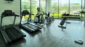 Uma academia moderna com esteiras, elípticos e um banco.