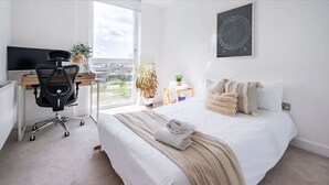 Quarto moderno com cama, escrivaninha e uma janela grande.