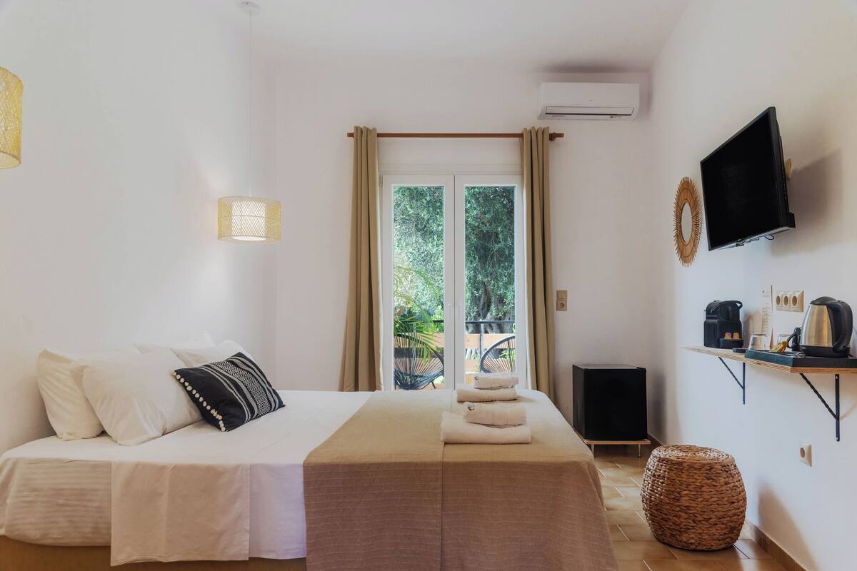 Quarto de hotel com cama, televisão, cantinho de café e vista para o exterior.