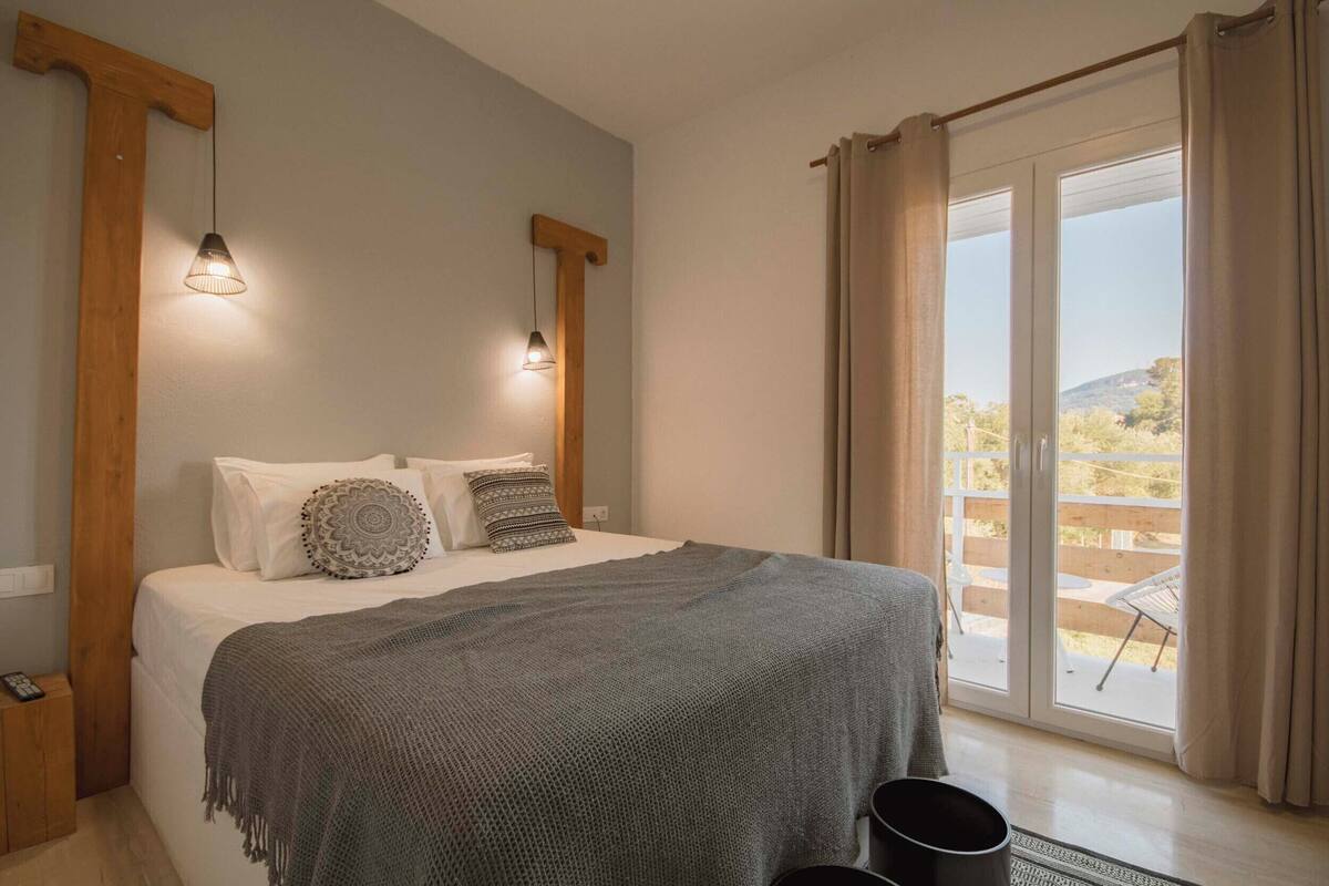 Quarto com cama, varanda e vista para o exterior.