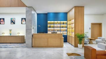 Uma área de recepção moderna com um balcão de madeira, uma parede azul destacada e uma exposição de prêmios.