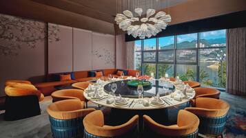 Uma sala de jantar moderna com uma mesa redonda posta para seis pessoas, rodeada por cadeiras laranjas.