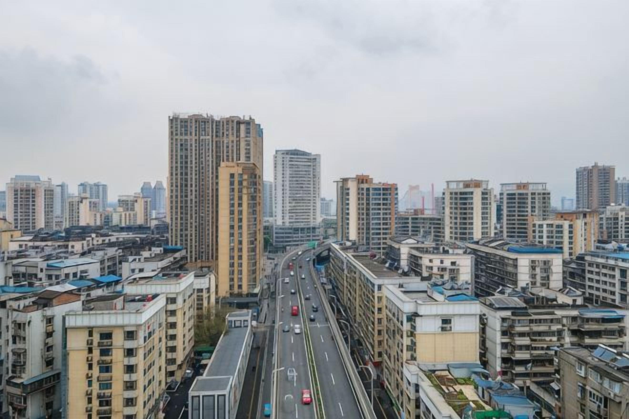 Paisagem urbana com edifícios altos, uma avenida com várias faixas e uma passarela para pedestres.