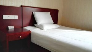 Quarto de hotel com uma cama de casal, uma mesa de cabeceira de madeira e uma tomada na parede.