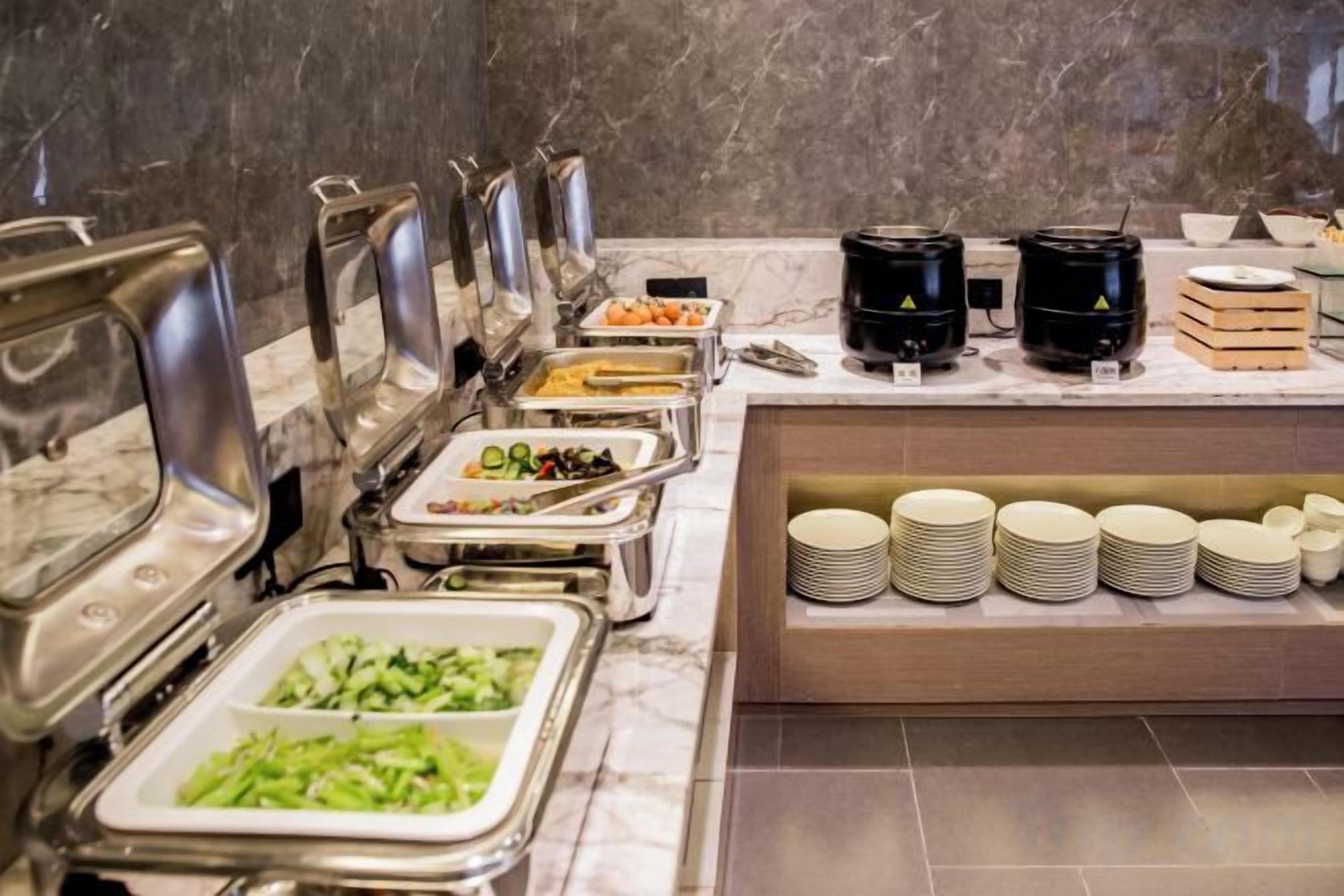 Disposição de buffet com diversos recipientes de comida e um espaço para café.