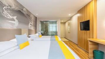 Quarto de hotel moderno com uma cama grande, TV fixada na parede e painel de madeira lateral.