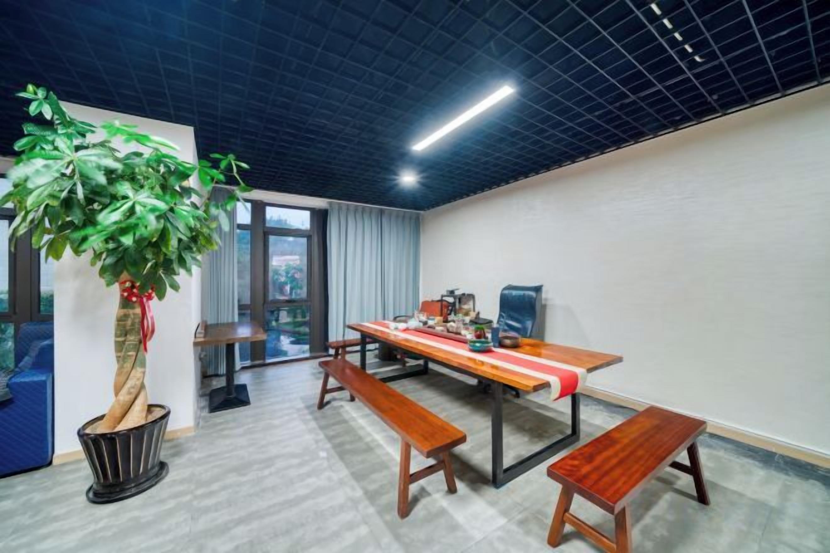 Um quarto com uma mesa de jantar, bancos, uma planta e uma janela.