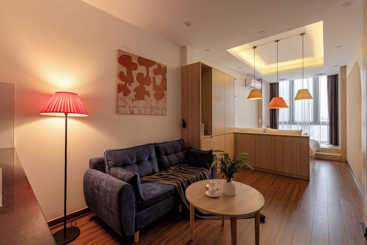 Uma sala de estar moderna com sofá, mesa de centro, luminária de chão e um quadro na parede.