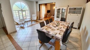 Uma sala de jantar com uma mesa grande, cadeiras e um armário com portas de vidro.