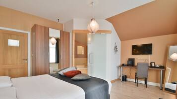 Quarto de hotel moderno com cama, escrivaninha, cadeira e televisão.