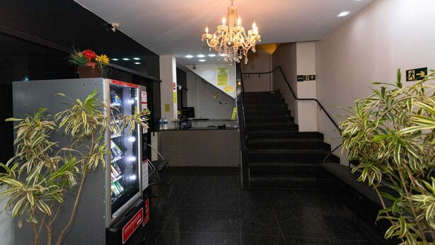 Uma área de recepção com máquina de vendas automática, escada e plantas em vasos.