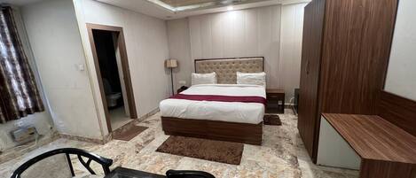 Quarto com cama, escrivaninha, cadeira e ventilador de teto.