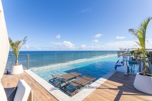 Área da piscina com espreguiçadeiras e vista para o mar.