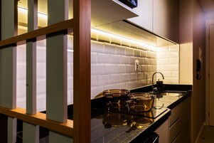 Uma cozinha com azulejos brancos tipo metrô, bancada preta e pia de aço inoxidável.