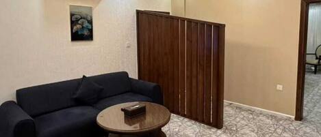 Uma sala de estar moderna com um sofá escuro, uma mesa de centro redonda e um painel de madeira.