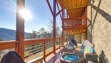 Um deck de madeira com hidromassagem, área de estar e vista para as montanhas.