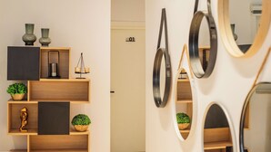 Um interior moderno com prateleiras de madeira, objetos decorativos e espelhos fixados na parede.
