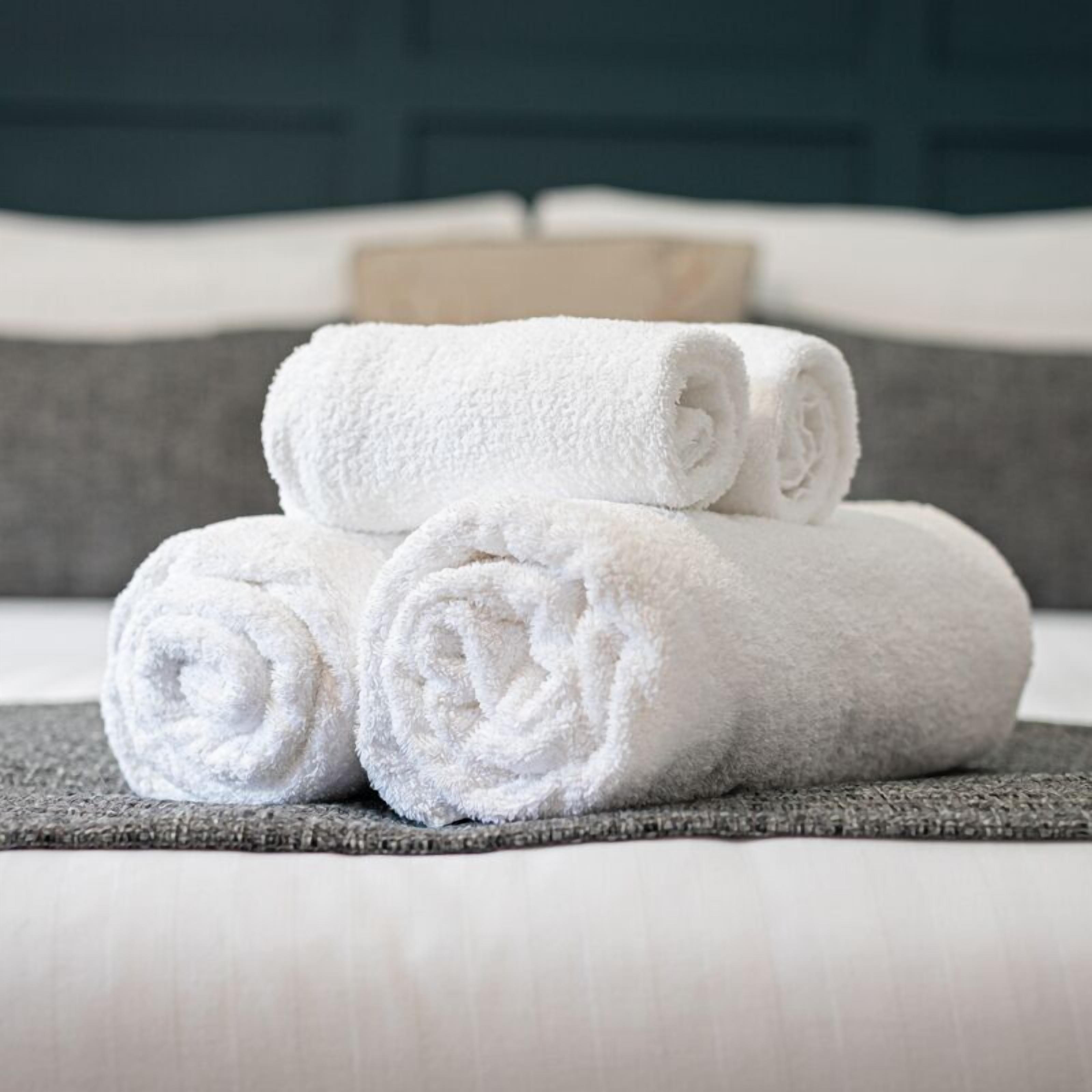 Uma pilha de toalhas brancas sobre uma superfície cinzenta num quarto de hotel.