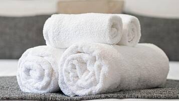 Uma pilha de toalhas brancas sobre uma superfície cinzenta num quarto de hotel.