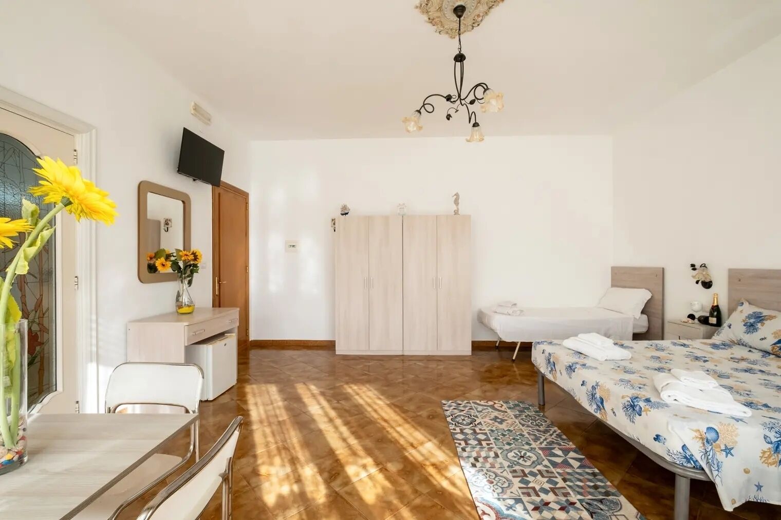 Quarto com cama, mesa de cabeceira, guarda-roupa e escrivaninha com cadeira.