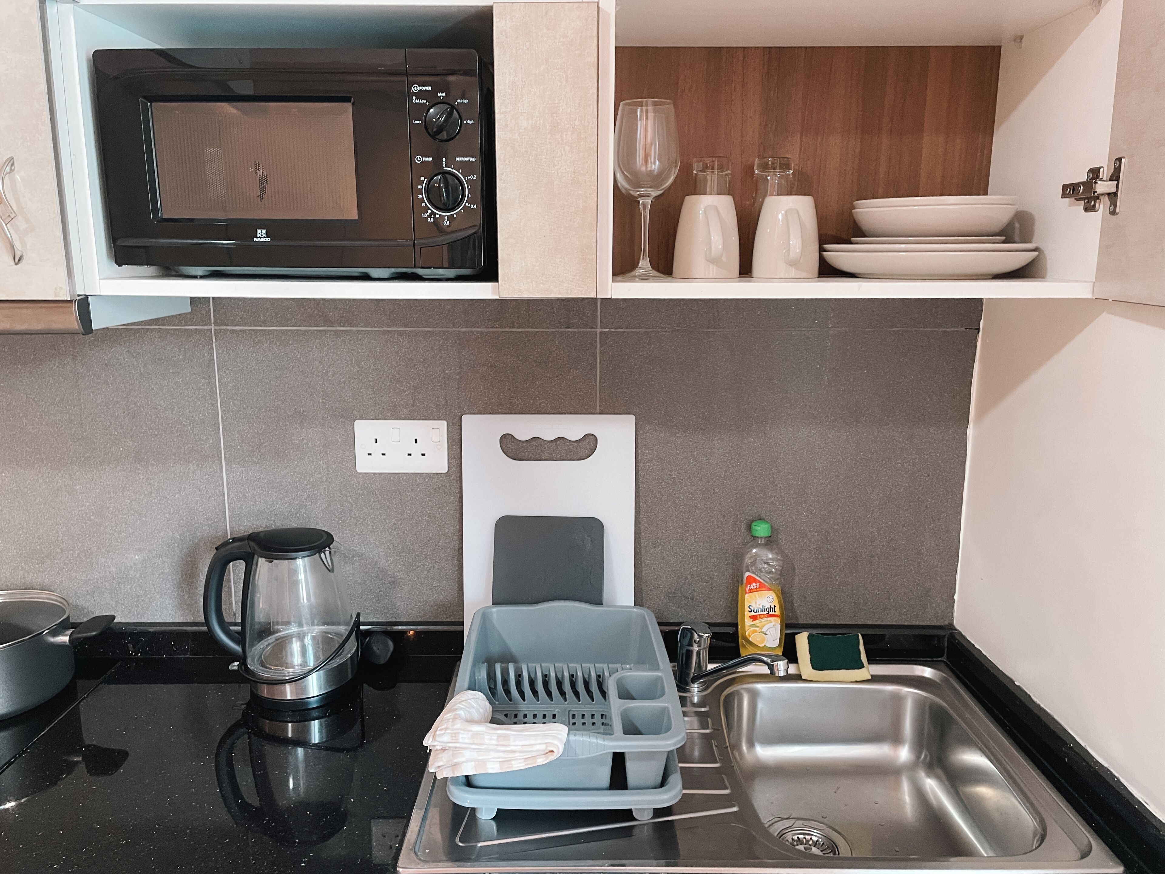 Uma cozinha compacta com micro-ondas, cafeteira e pia.