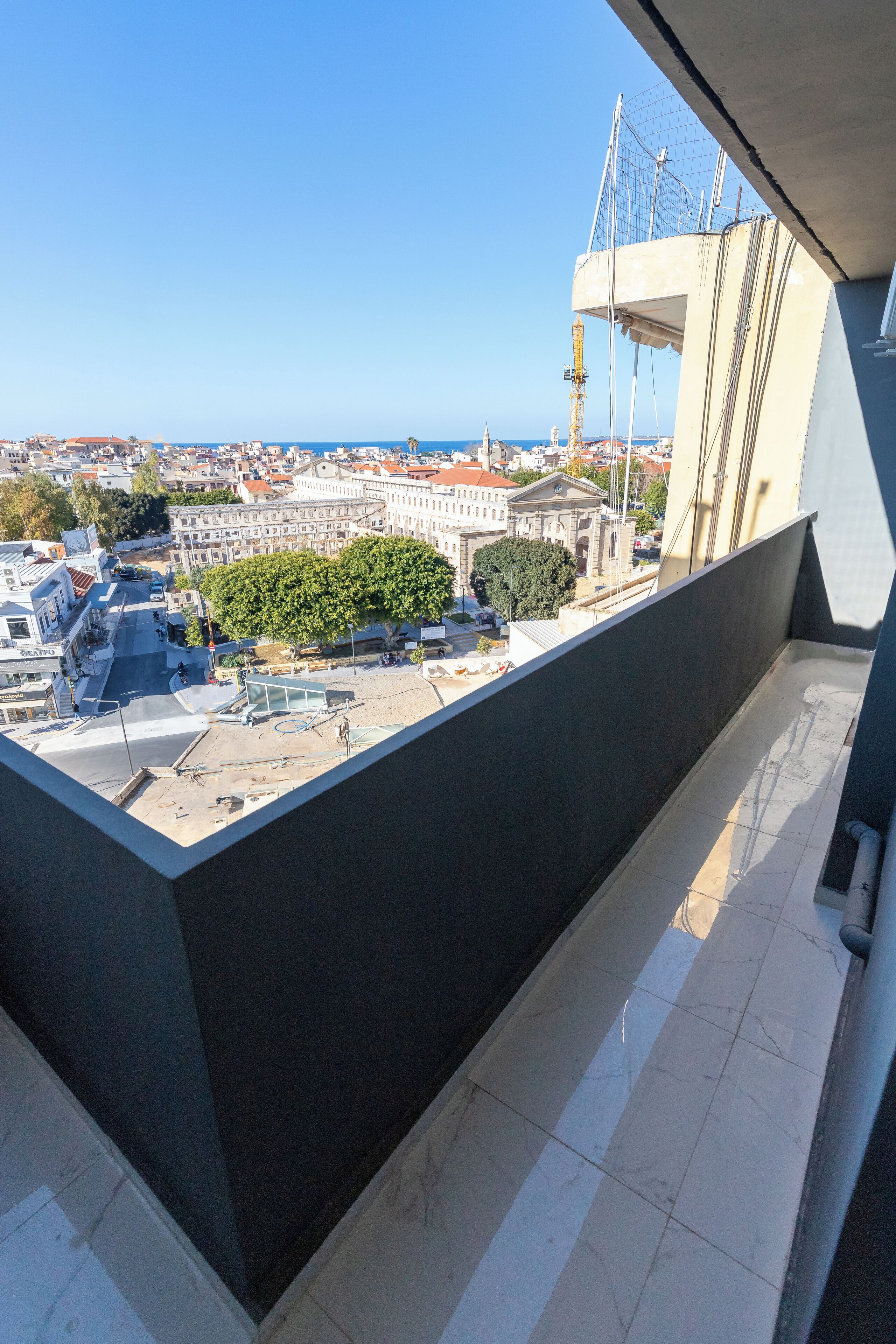 Uma varanda com vista para a paisagem urbana, incluindo edifícios e um canteiro de obras.