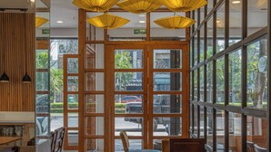 Interior de restaurante com mobiliário de madeira, janelas amplas e luminárias amarelas penduradas.