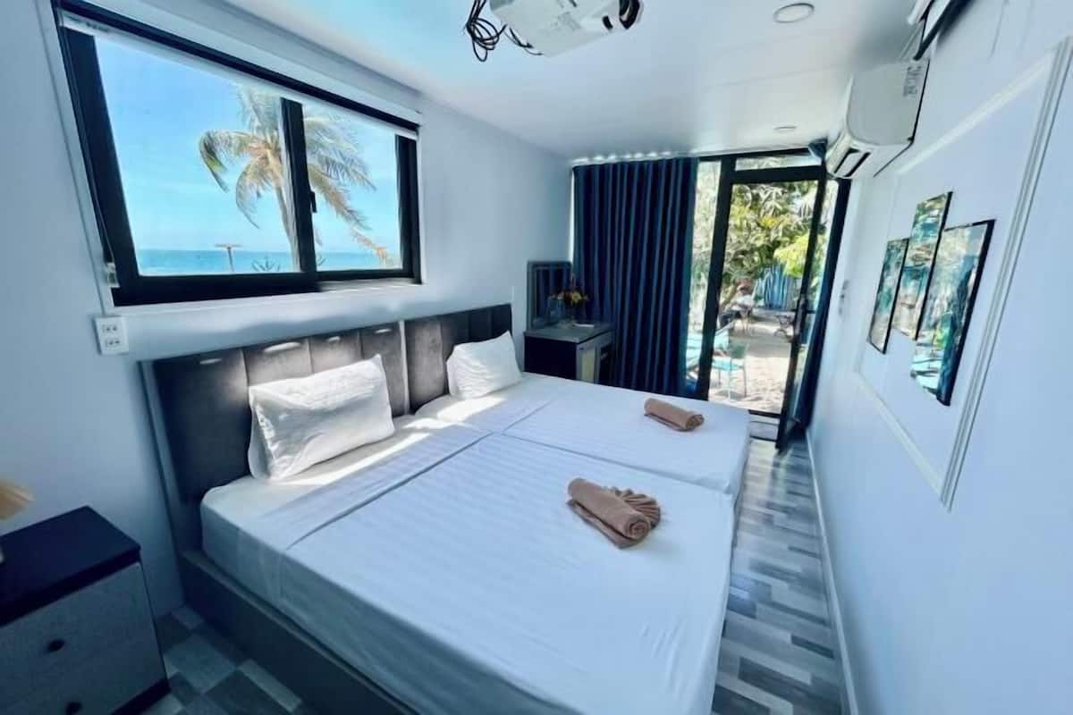 Quarto de hotel com cama grande, mesa de trabalho, janela com vista e varanda.