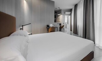 Quarto de hotel moderno com uma cama grande, uma mesa e uma cadeira.