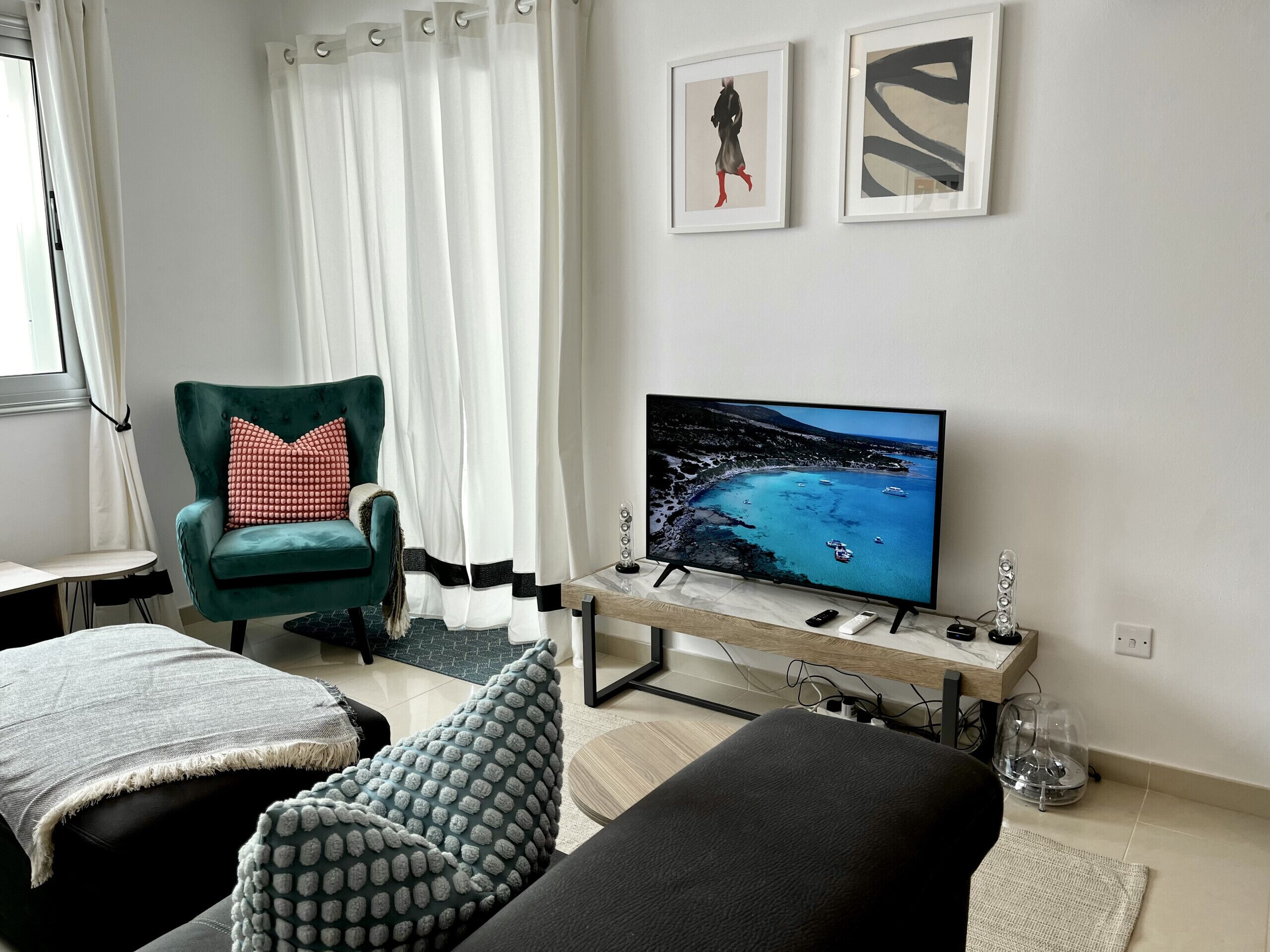 Uma sala de estar moderna com uma grande televisão de tela plana, uma poltrona verde-água e um sofá.
