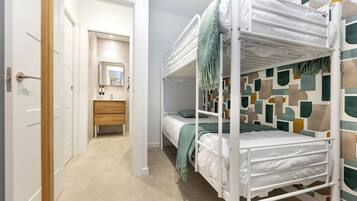 Quarto com beliche, cômoda de madeira, espelho e parede com padrão geométrico.