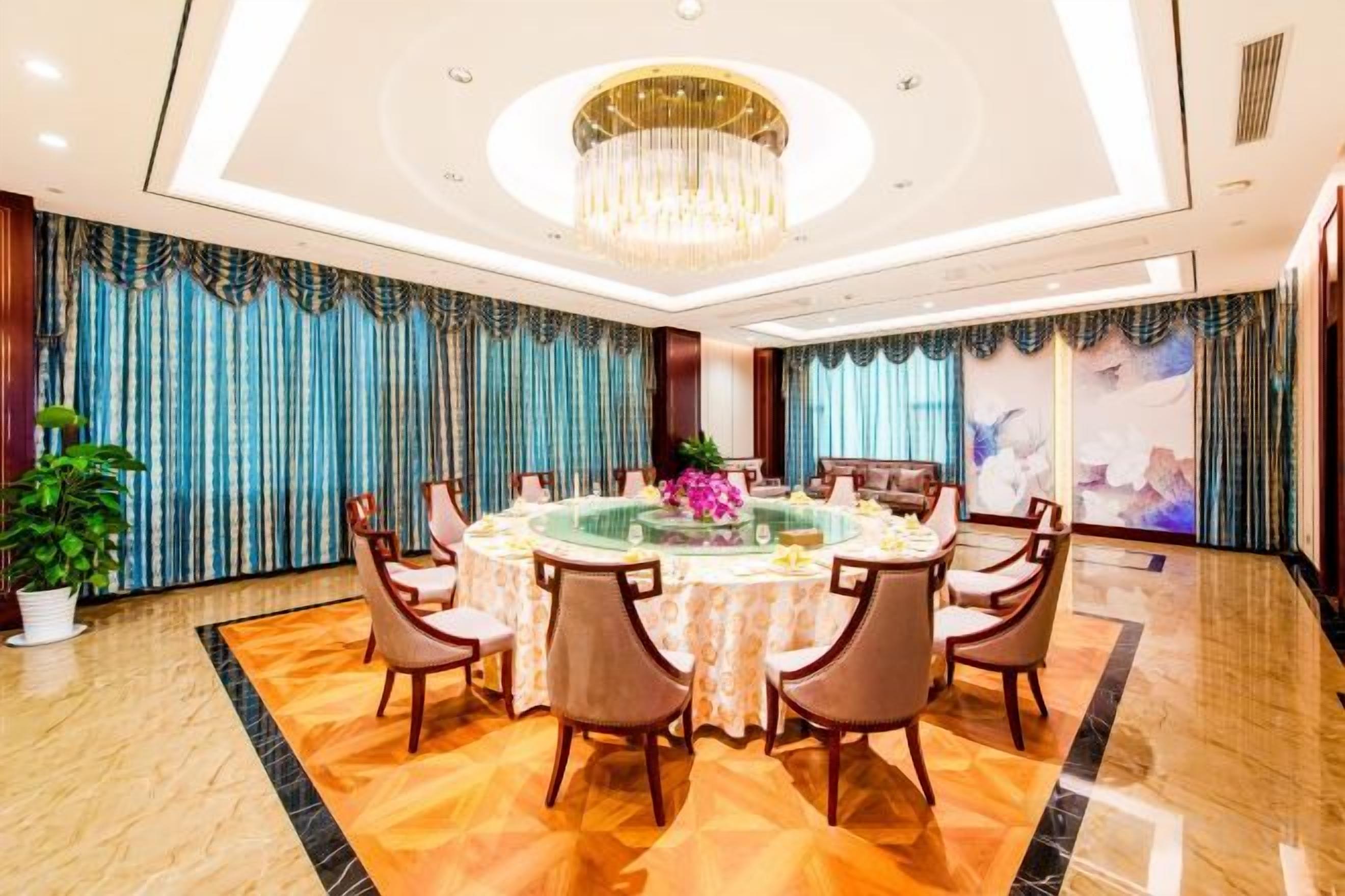 Sala de conferência com uma mesa redonda, cadeiras e um candelabro.