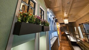 Um corredor com uma caixa de flores na parede, um relógio e uma área de cozinha com bancada e armários.