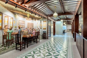 Um restaurante com mesas e cadeiras de madeira, piso estampado e lanternas penduradas.