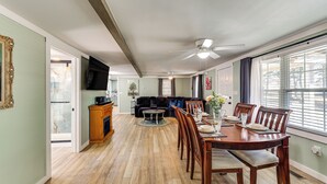 Uma sala de jantar com uma mesa de madeira, cadeiras e um ventilador de teto.