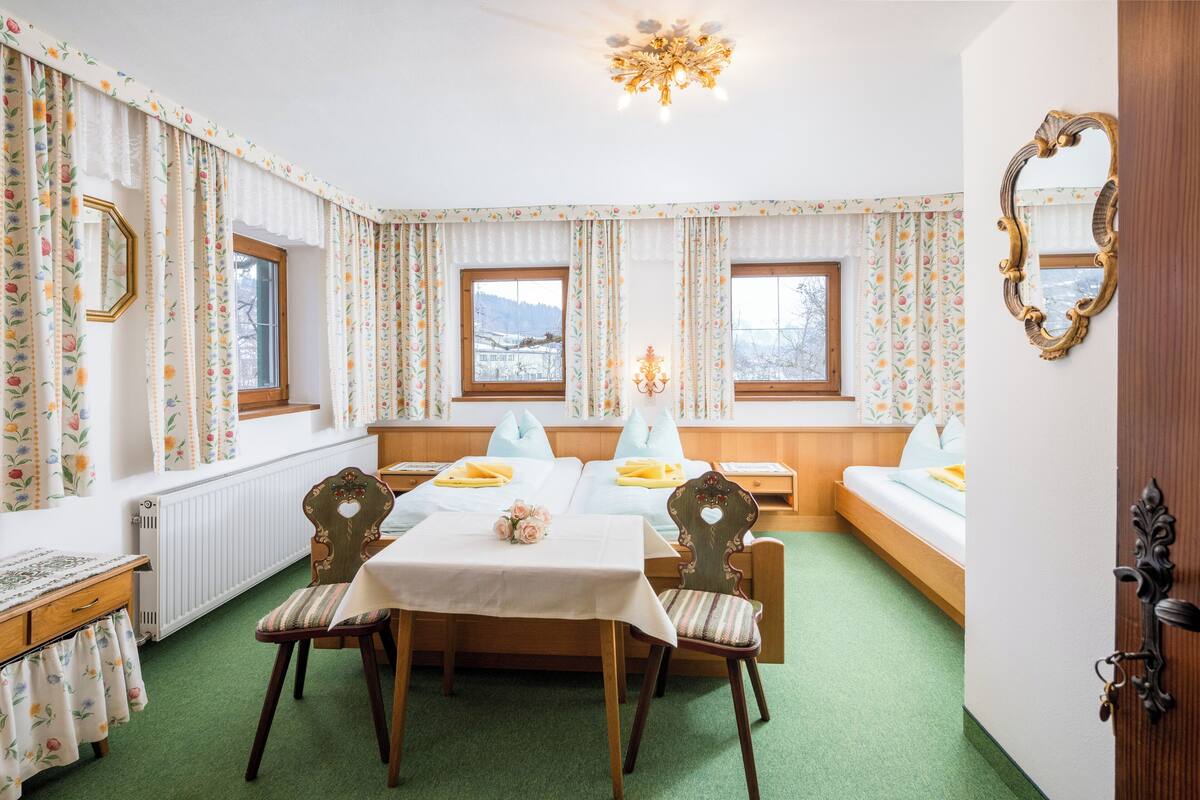 Quarto com uma mesa de jantar, duas cadeiras, um banco e vista para as montanhas pelas janelas.