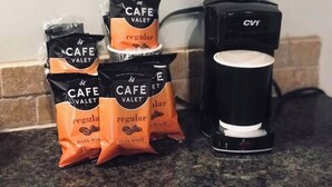 Máquina de café e vários sachês de café Cafe Valet em uma bancada de cozinha.