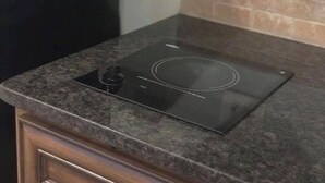 Uma cozinha com um fogão por indução embutido em uma bancada de granito.
