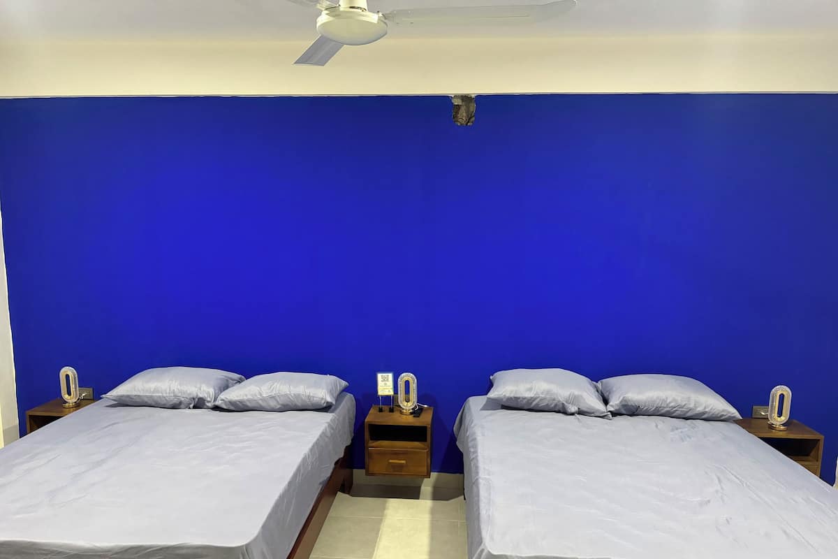 Quarto com duas camas, cada uma com mesa de cabeceira e luminária.