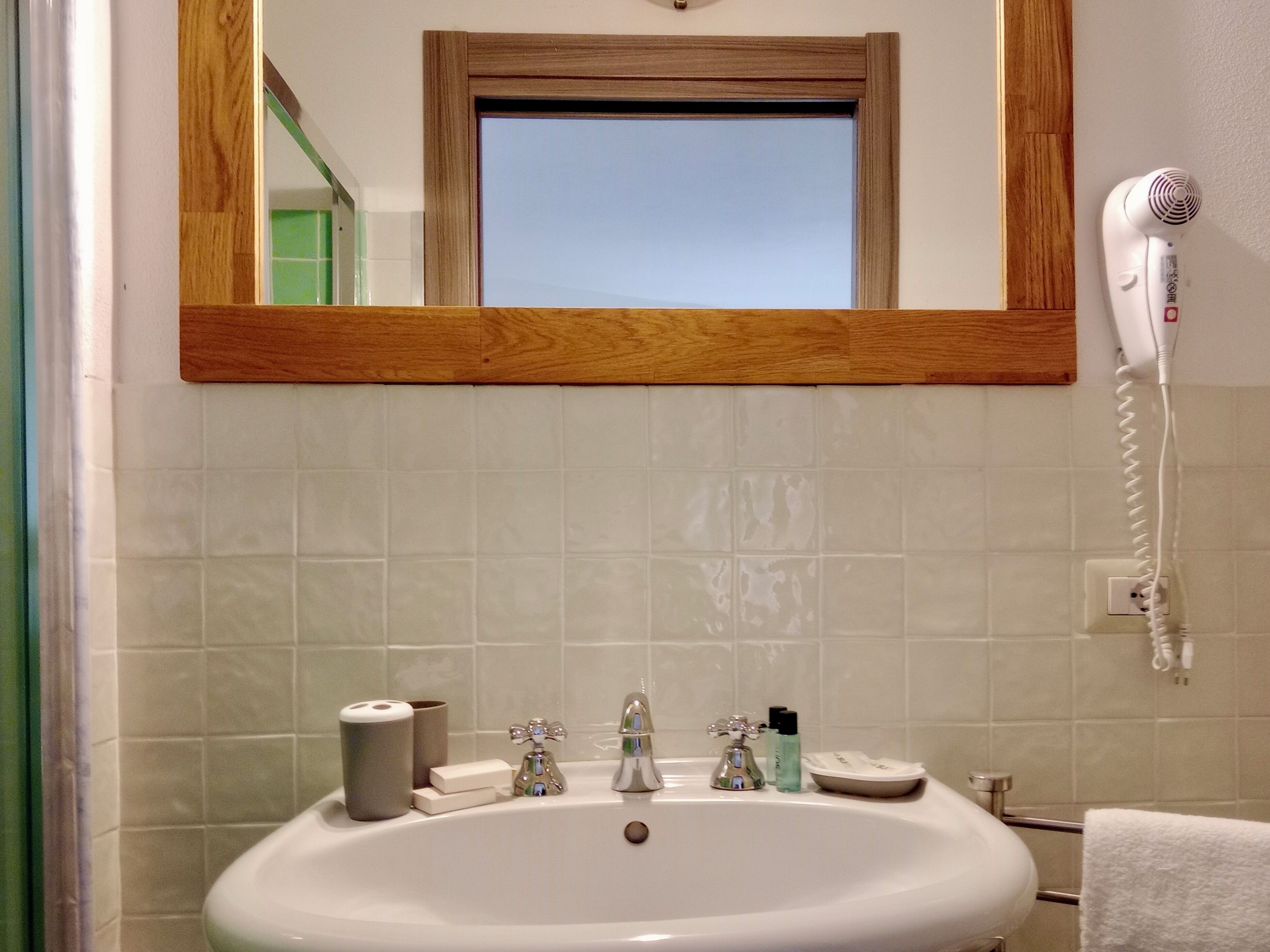 Casa de banho com lavatório, espelho e secador de cabelo.