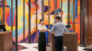 Um lobby com uma parede abstrata colorida, um balcão de recepção e um balcão de check-in.