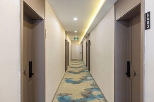 Corredor de hotel com portas em ambos os lados, carpete com padrão floral e placa indicando a sala número 6403.