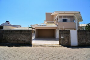 Uma casa de dois andares com garagem, varanda e telhado com telhas.